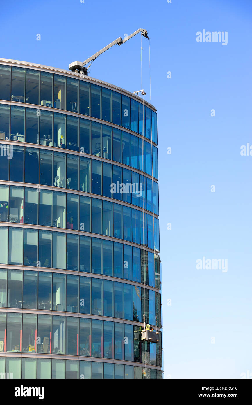 Men using a cradle hoist on 2 More London Riverside glass window facade ...
