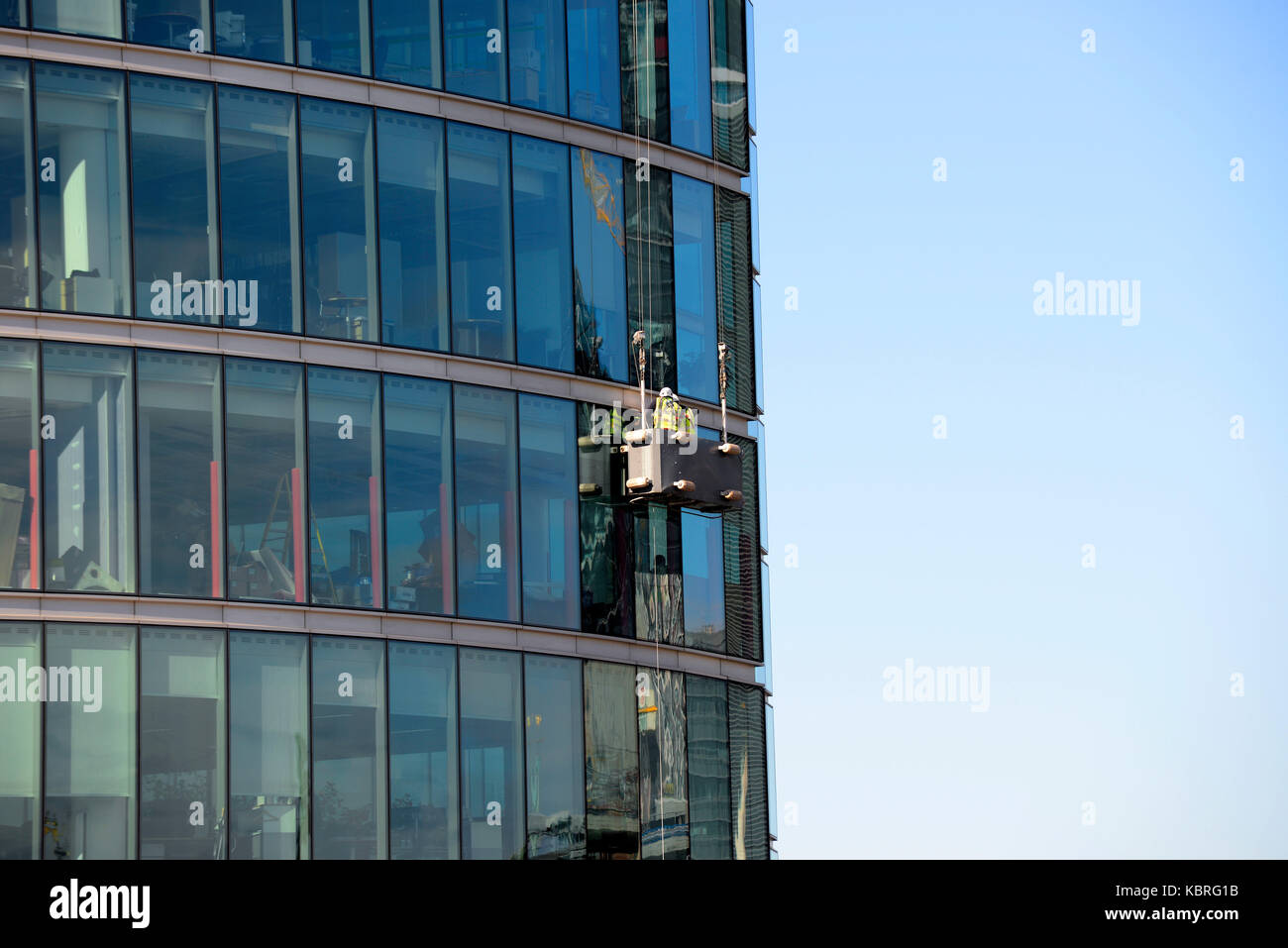 Men using a cradle hoist on 2 More London Riverside glass window facade ...