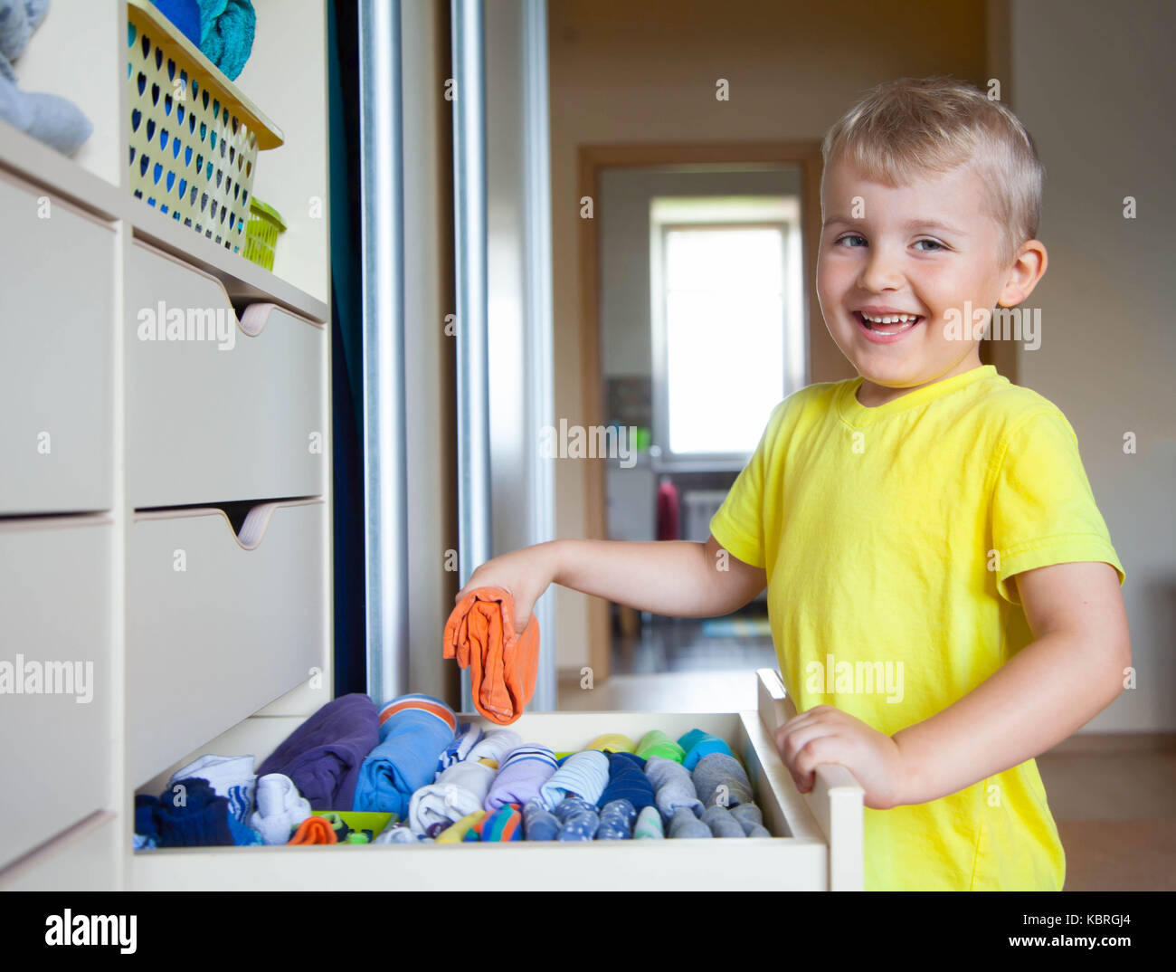The child puts his clothes on. The boy pulls the T-shirt out of the ...