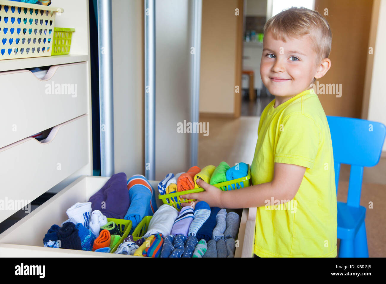 The child puts his clothes on. The boy pulls the T-shirt out of the ...