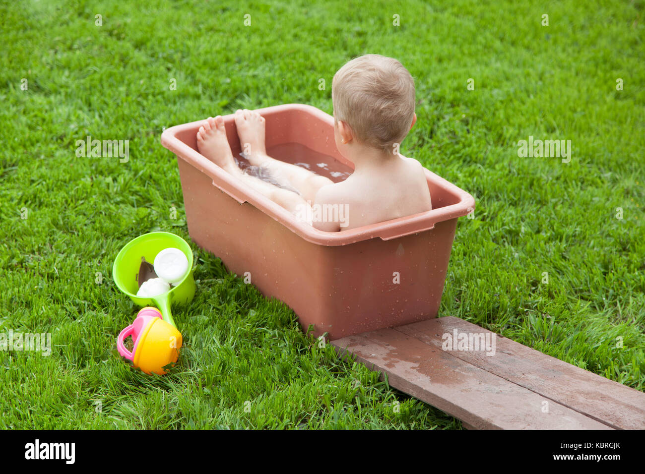 little boy washes in the bathroom on the green grass. Kid 4-5 year old ...