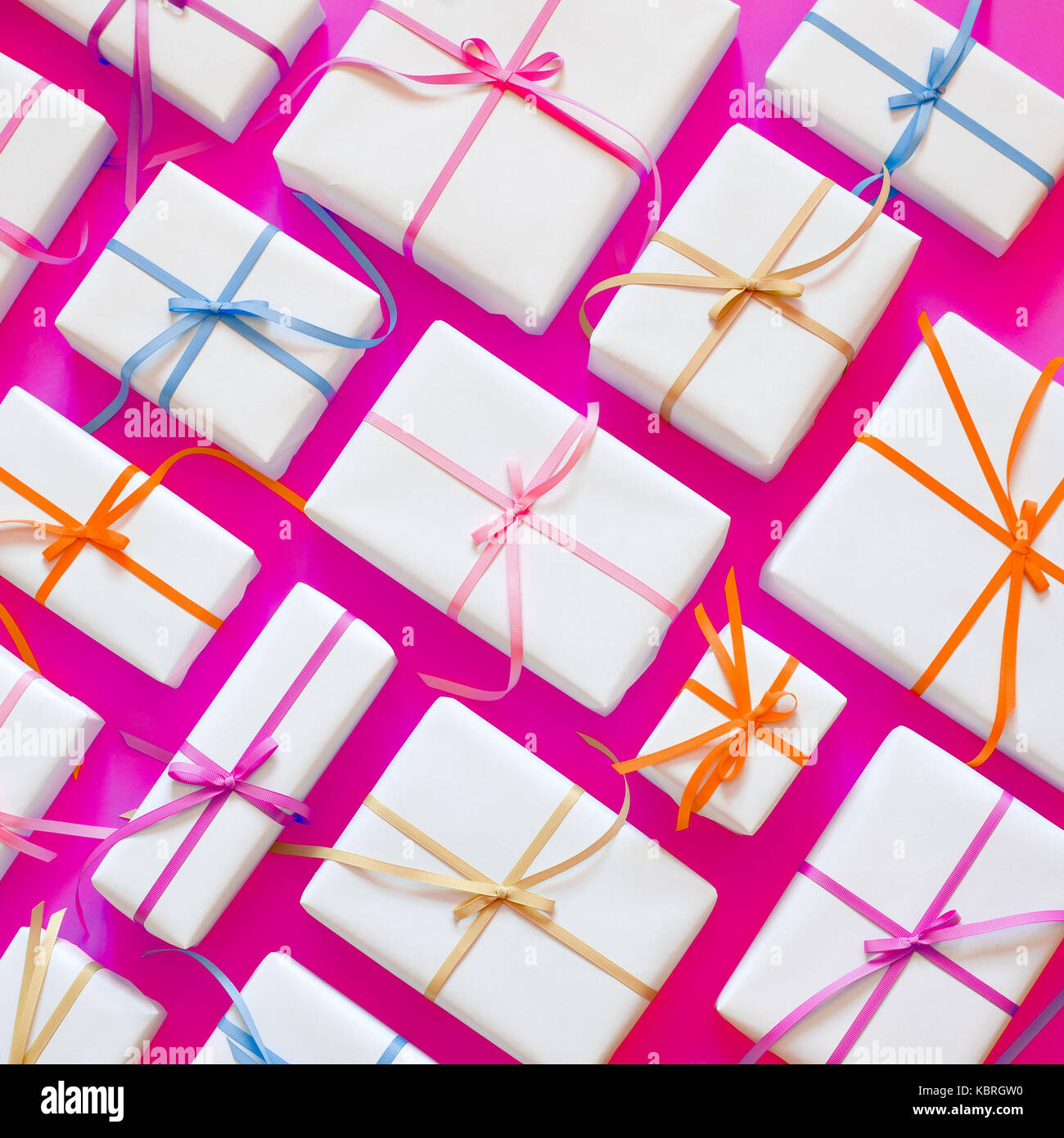 Bright pink background. Many gifts of different sizes. White gift boxes ...
