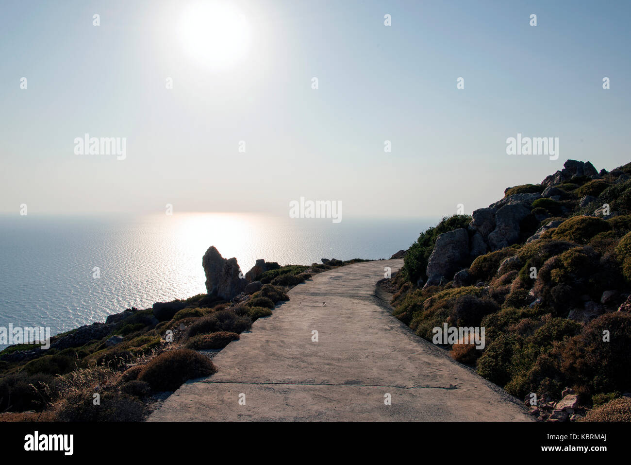 A concrete pathway in the mountain behind the sunset and the sea Stock ...
