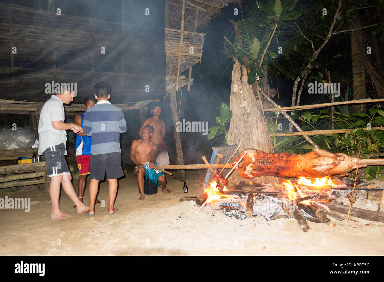 Philippines holiday - staff and tourists at a beach barbecue hog roast ...