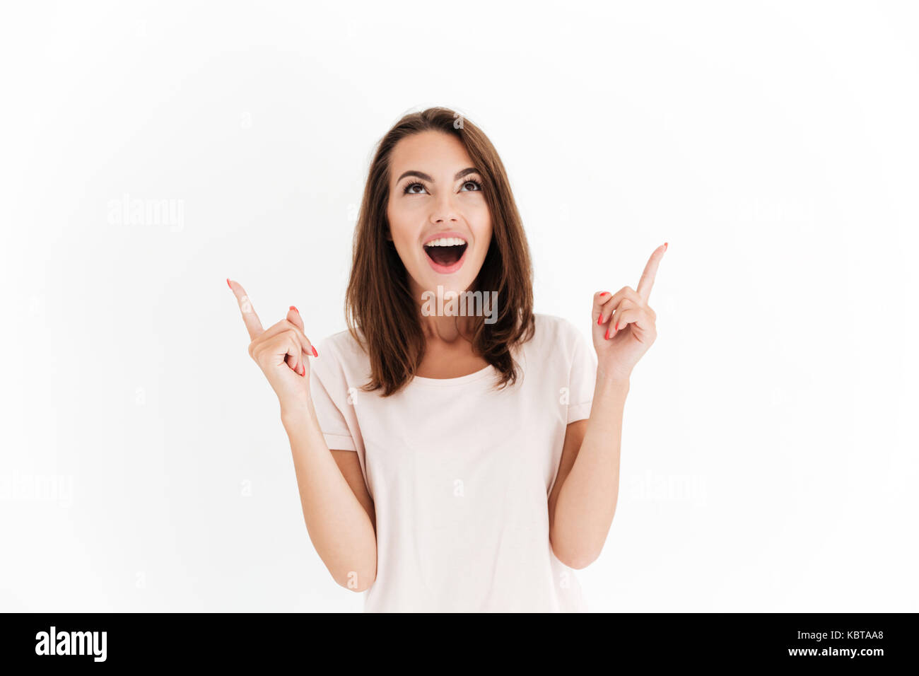 Happy screaming woman pointing and looking up over white background ...