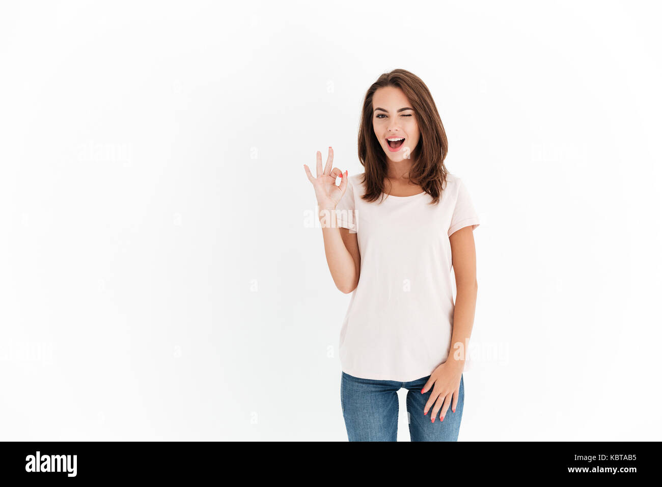 Attractive woman showing ok sign and winks at the camera over white ...