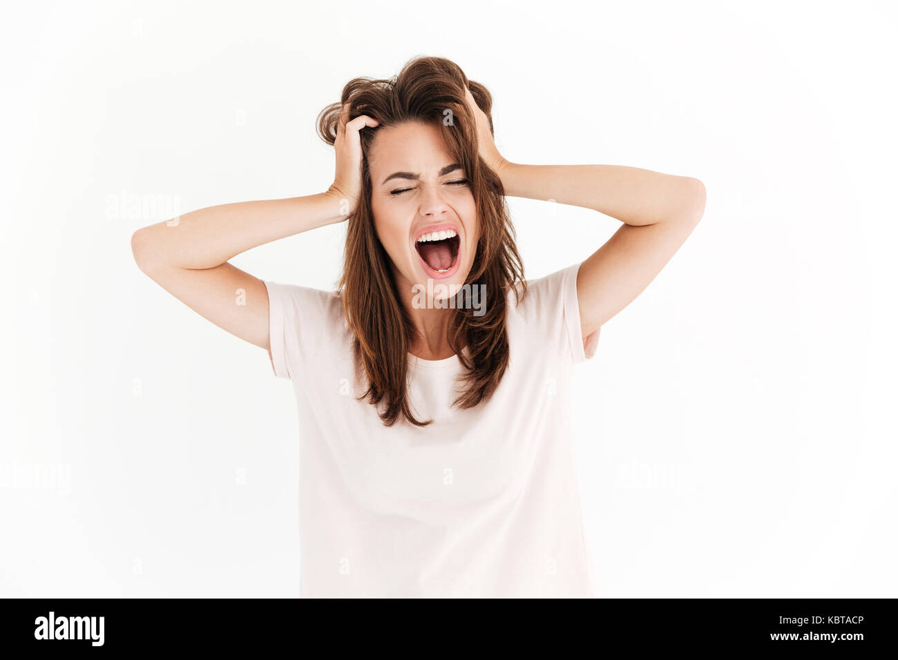 Screaming brunette woman in stress holding her head over white ...