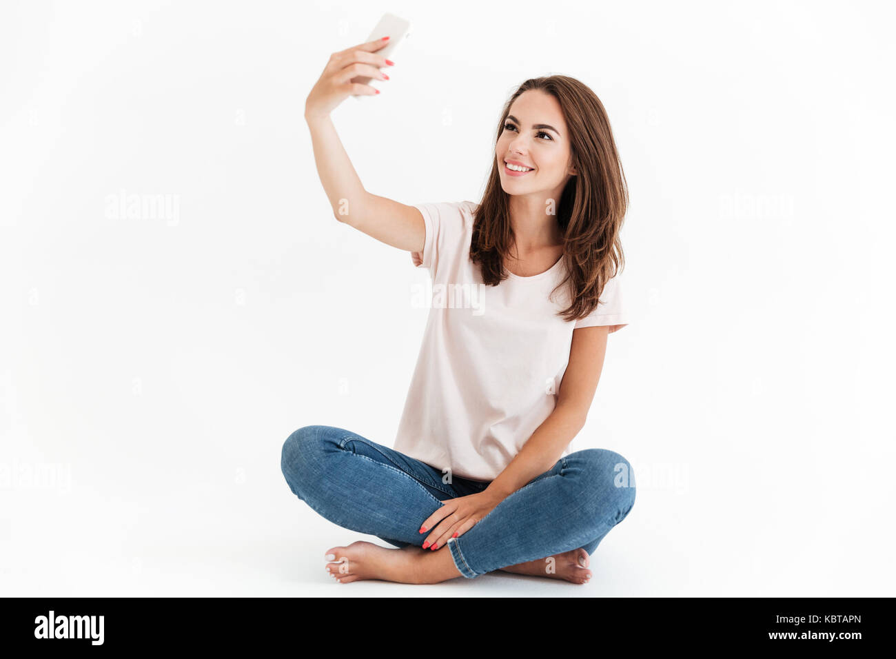 Smiling brunette woman sitting on the floor and making selfie on ...