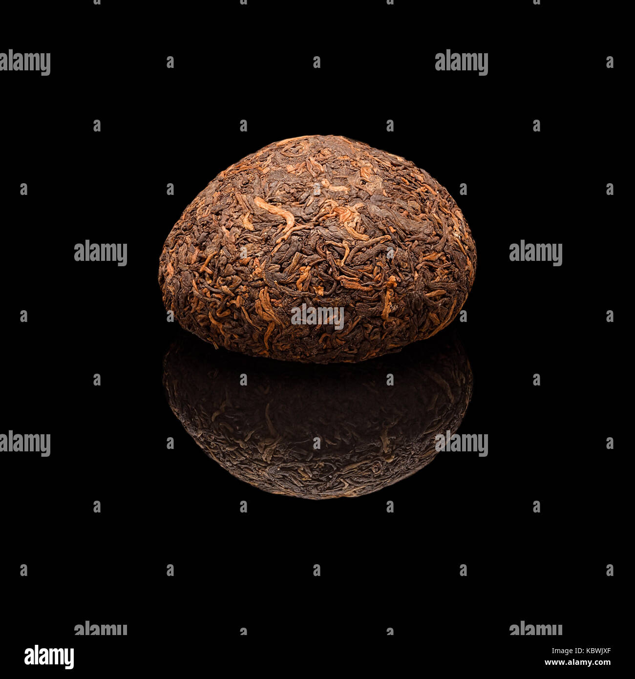 Block of pressed Chinese Puer tea. On a black glossy background with ...