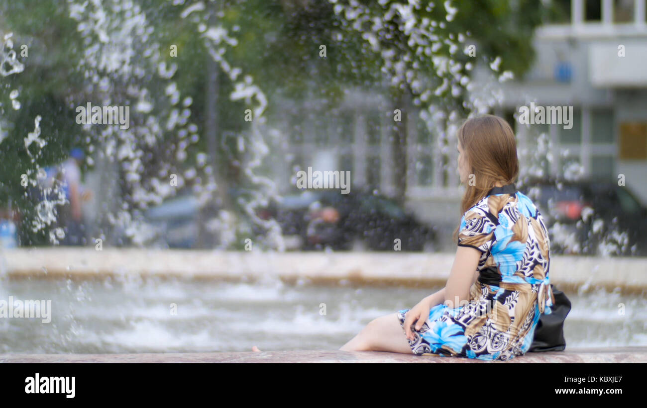 Girl sitting, in the background is a flowing fountain. Girl sitting at ...
