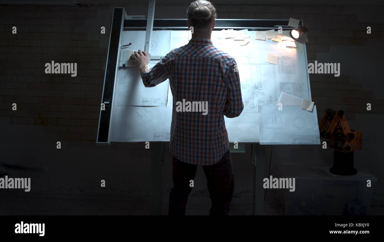 Young engineer standing at the white board with drawing and plan back ...