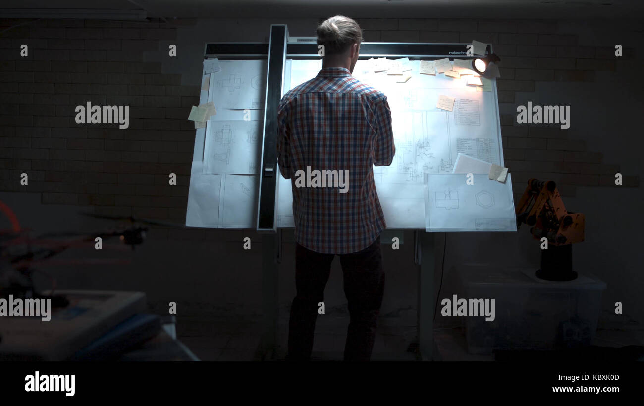 Young engineer standing at the white board with drawing and plan back ...