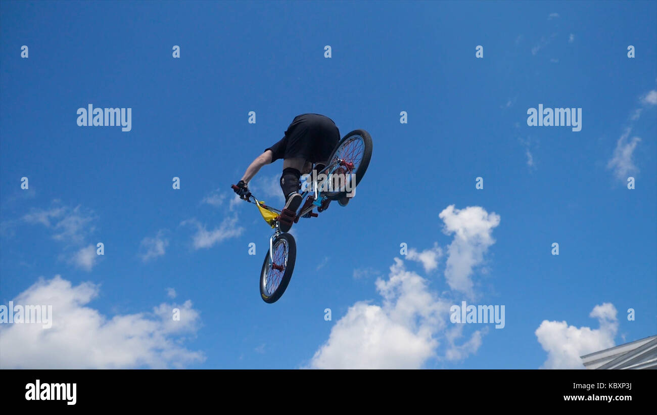 Young man on BMX bike jumps. Man doing twists and tricks on bmx in slow ...