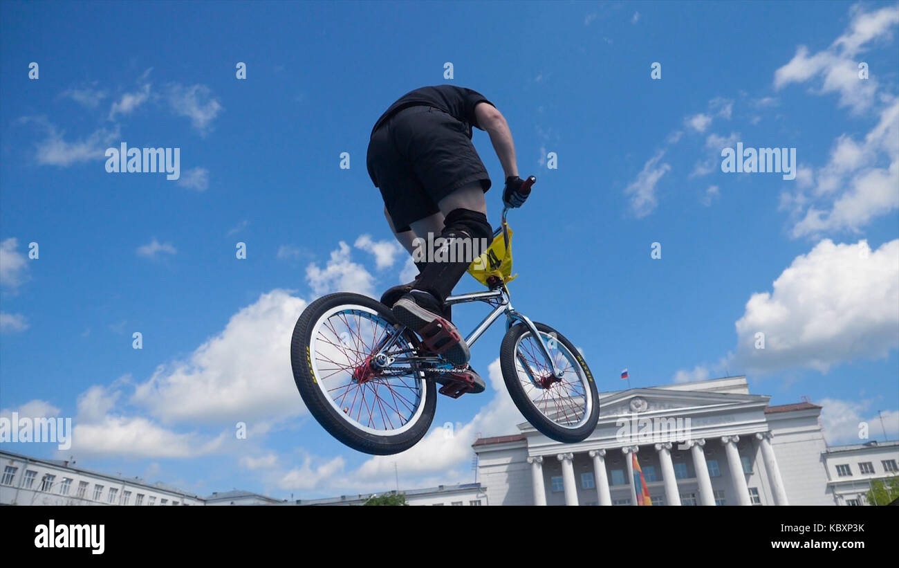 Young man on BMX bike jumps. Man doing twists and tricks on bmx in slow ...