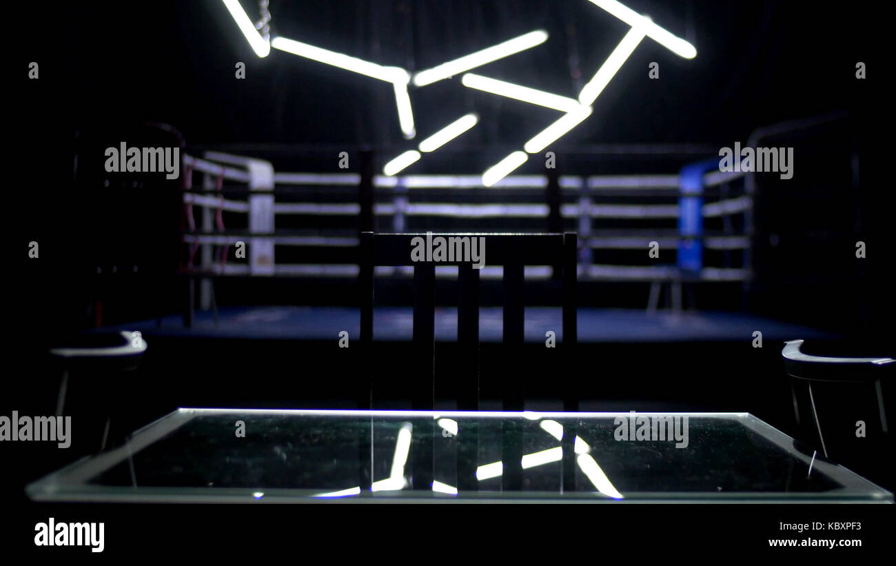 Boxing ring and two chairs with table dark background. View of a ...