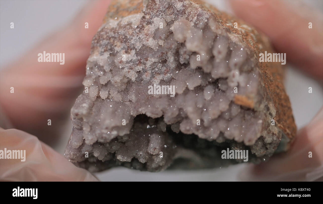 Bright grey ruby crystal ore in hands with gloves. Crystallization is ...