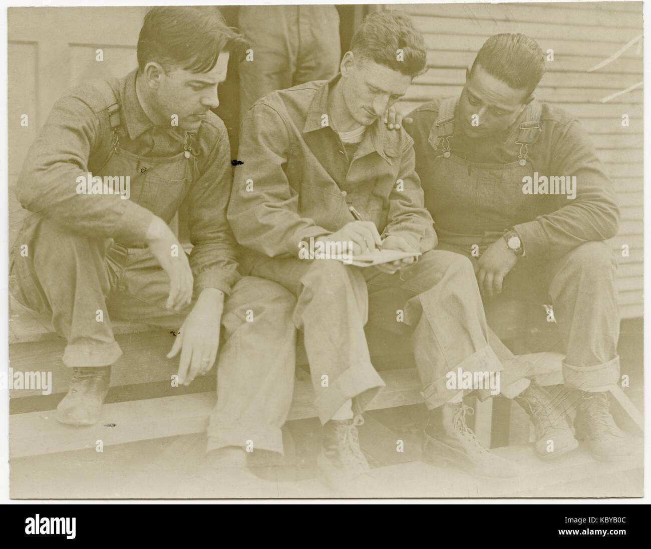 A Group of Soldiers Sitting on Wooden Steps Watching One Soldier Write ...