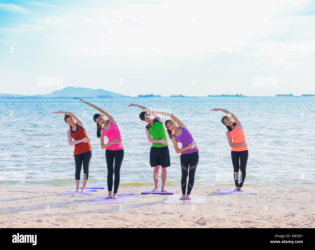 Yoga class at sea beach in evening ,Group of people doing Standing Side ...