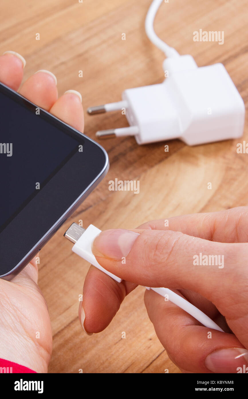 Hand of woman connects plug of charger mobile phone, smartphone ...