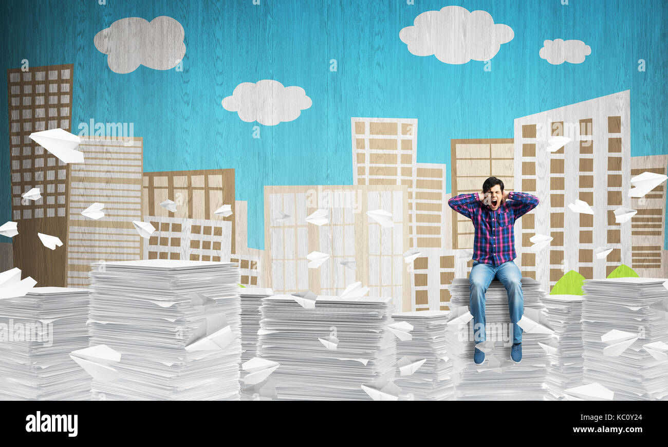 Young man sitting on pile of paper documents Stock Photo - Alamy