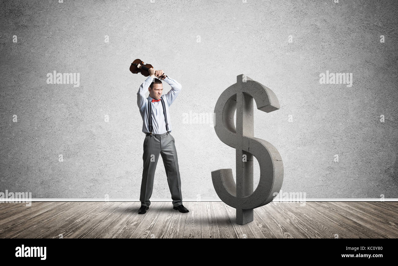 Determined banker man in empty concrete room breaking dollar figure ...