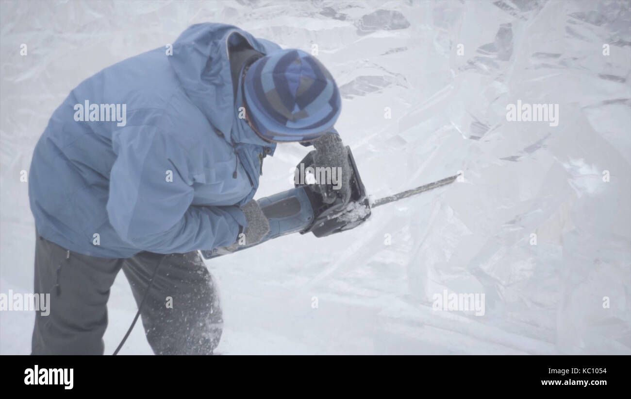 View of sculptor carving ice. Movement. Cut ice with a chainsaw. Cut ...