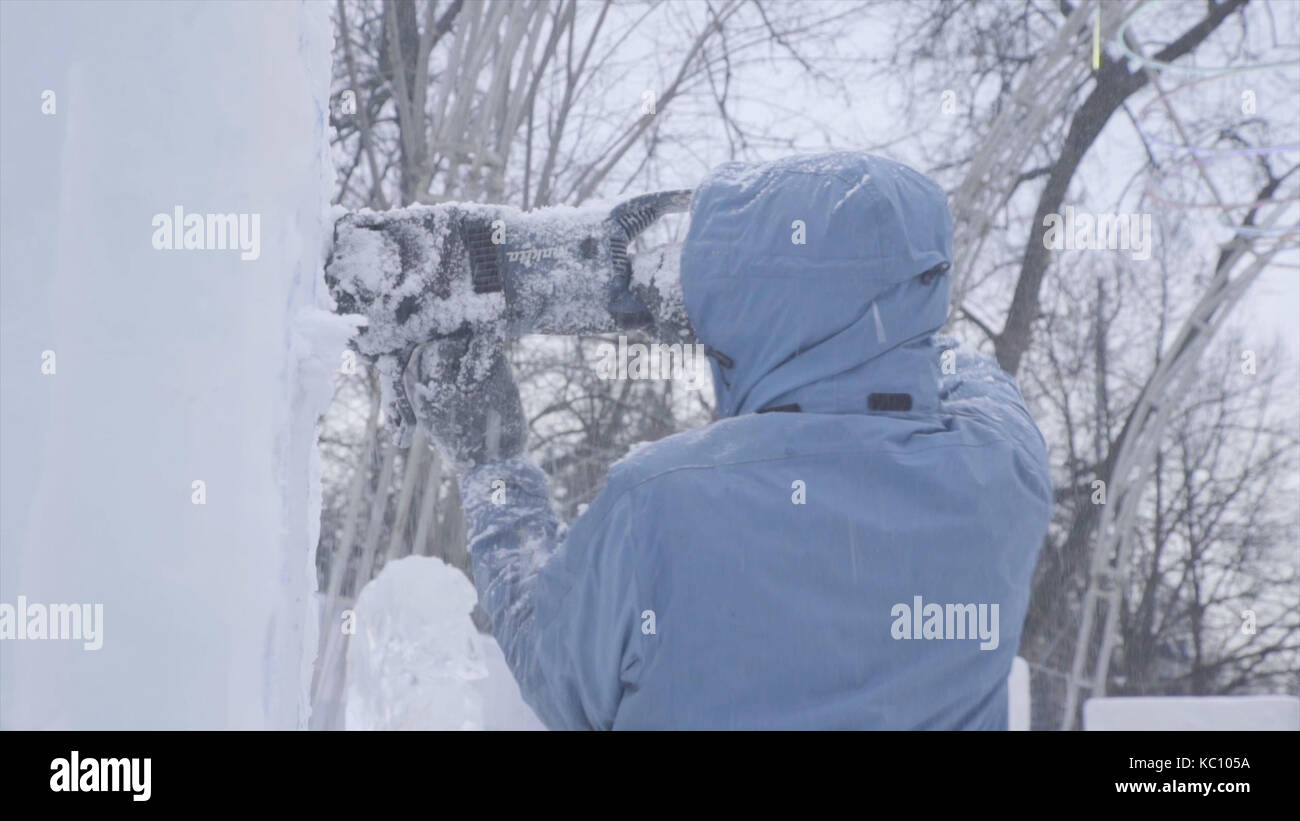 View of sculptor carving ice. Movement. Cut ice with a chainsaw. Cut ...