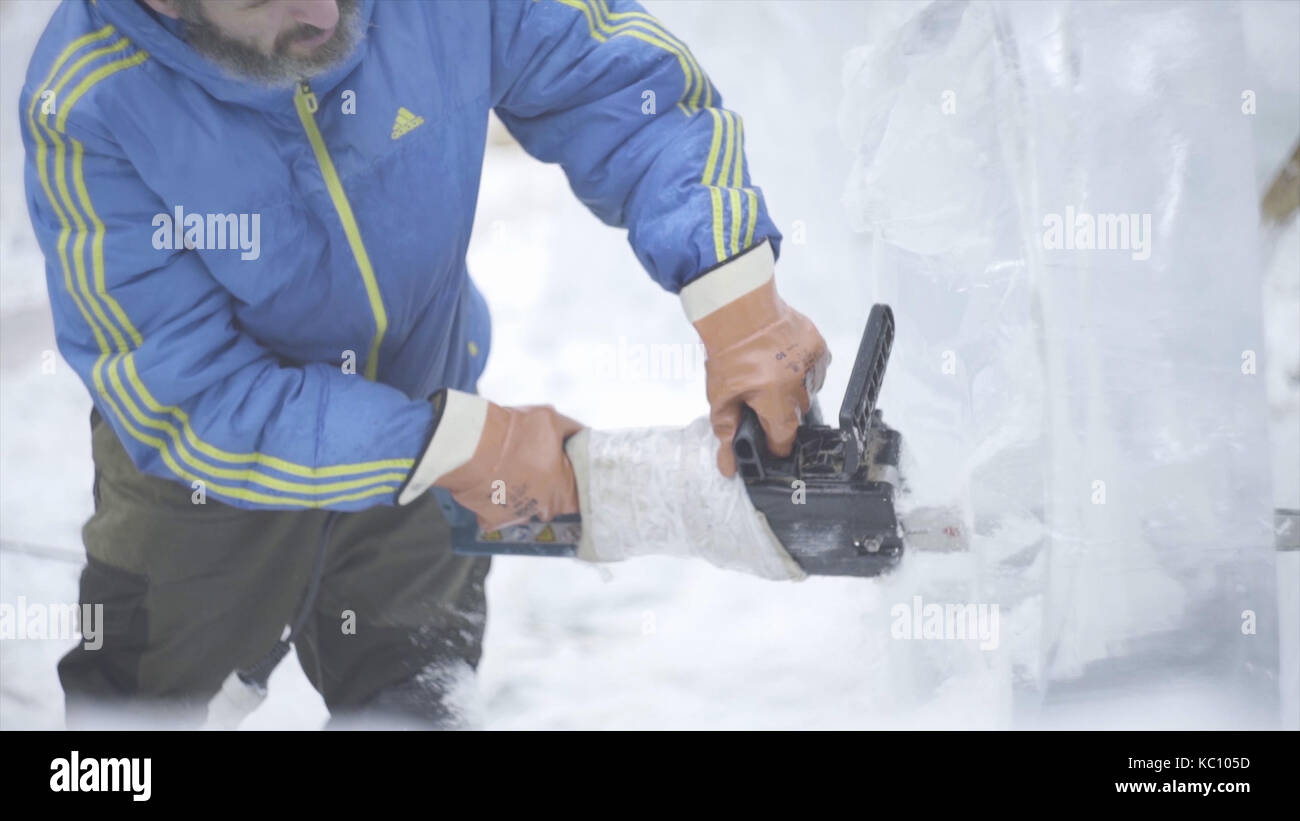 View of sculptor carving ice. Movement. Cut ice with a chainsaw. Cut ...