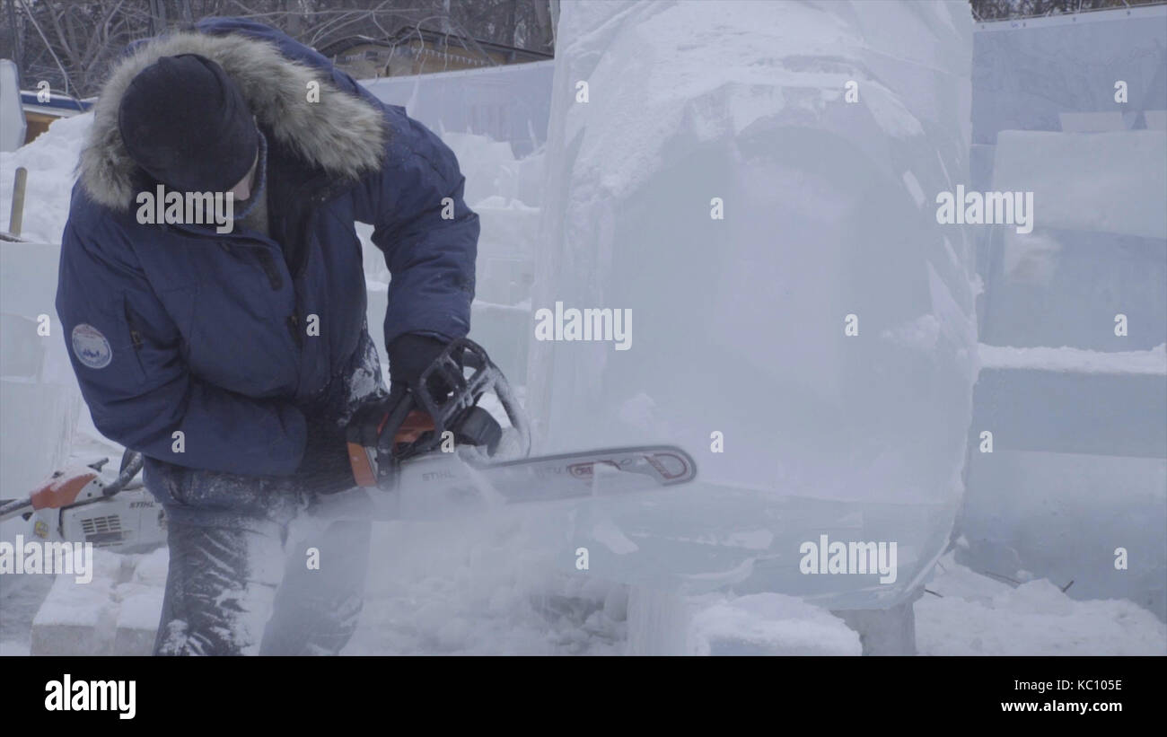 View of sculptor carving ice. Movement. Cut ice with a chainsaw. Cut ...