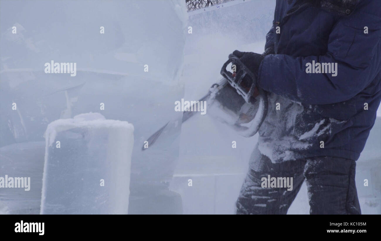 View of sculptor carving ice. Movement. Cut ice with a chainsaw. Cut ...