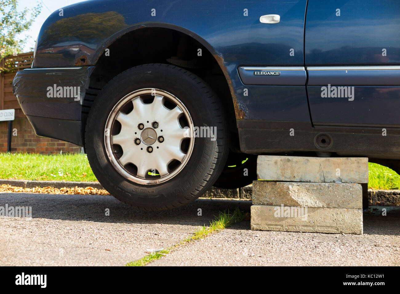 A Mercedes saloon car resting on a pile of bricks as part of a DIY home ...