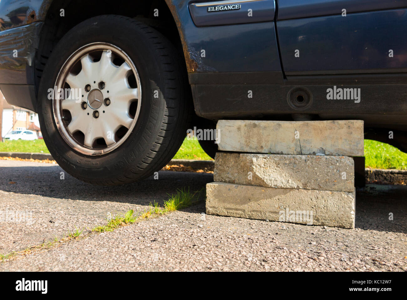 A Mercedes saloon car resting on a pile of bricks as part of a DIY home ...