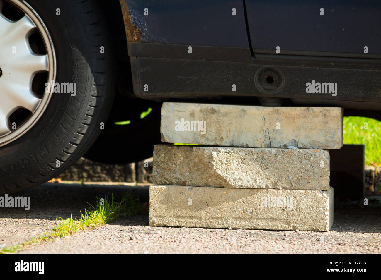 A Mercedes saloon car resting on a pile of bricks as part of a DIY home ...