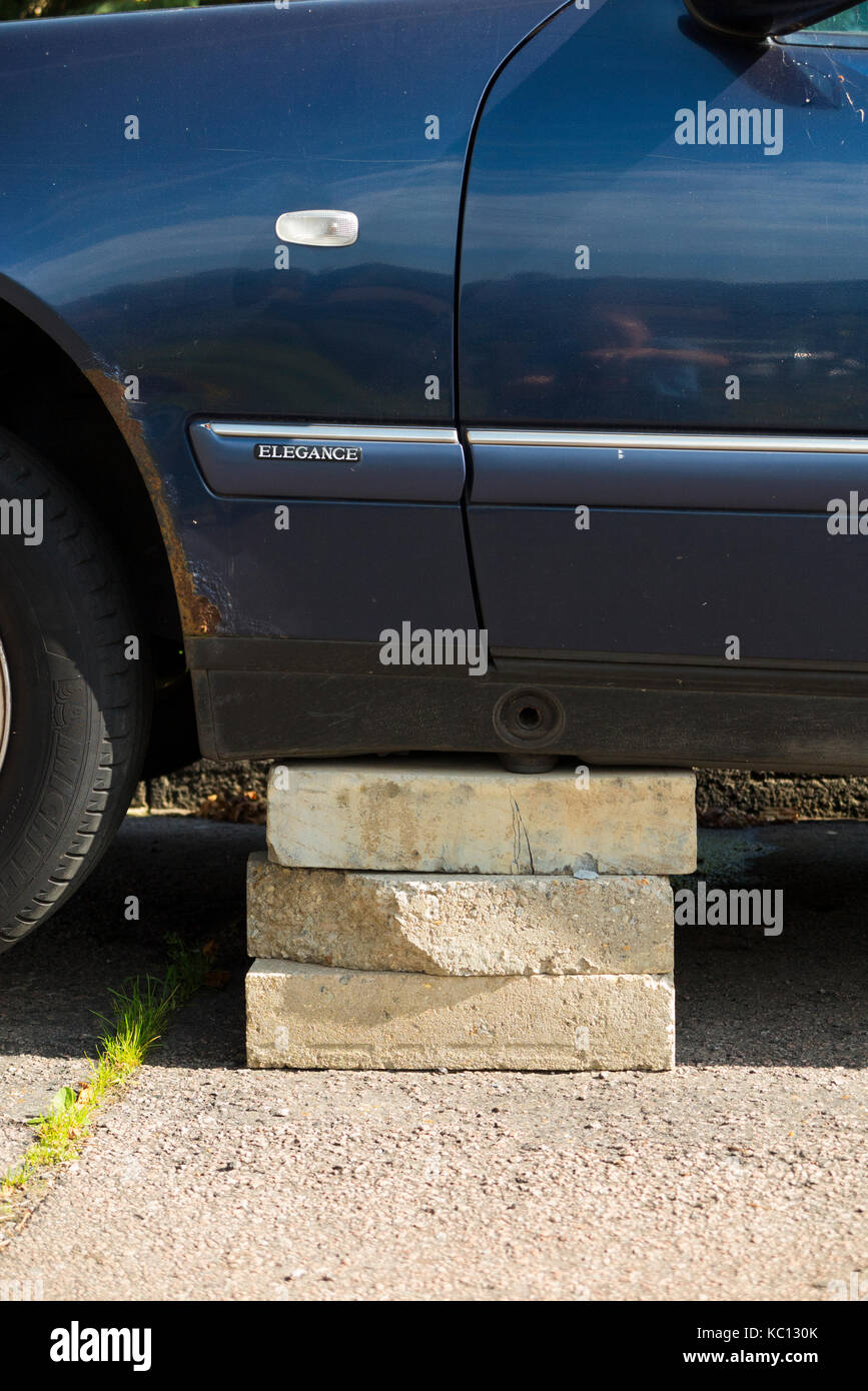 A Mercedes saloon car resting on a pile of bricks as part of a DIY home ...