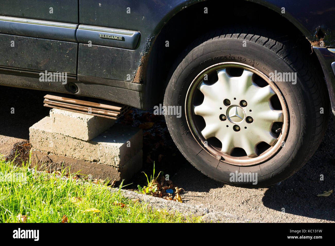 A Mercedes saloon car resting on a pile of bricks as part of a DIY home ...