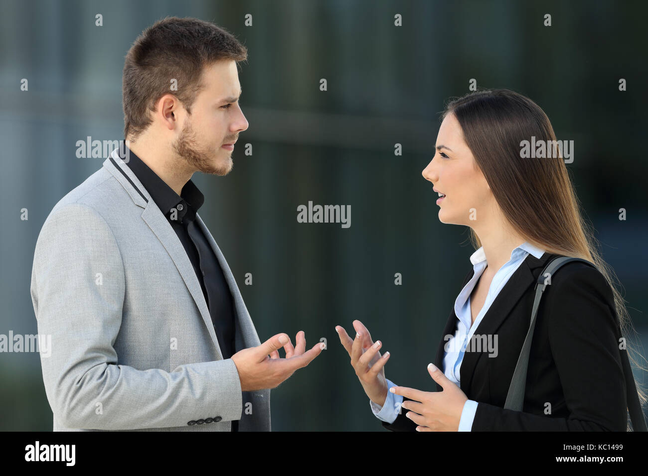 Side view portrait of two executives talking seriously standing ...