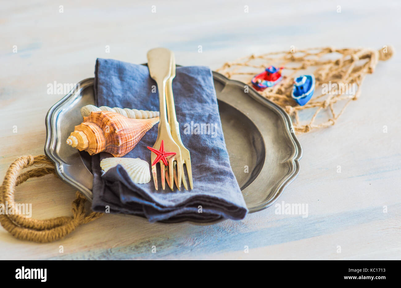 Summer vacation marine table setting with rustic plates and silverware ...