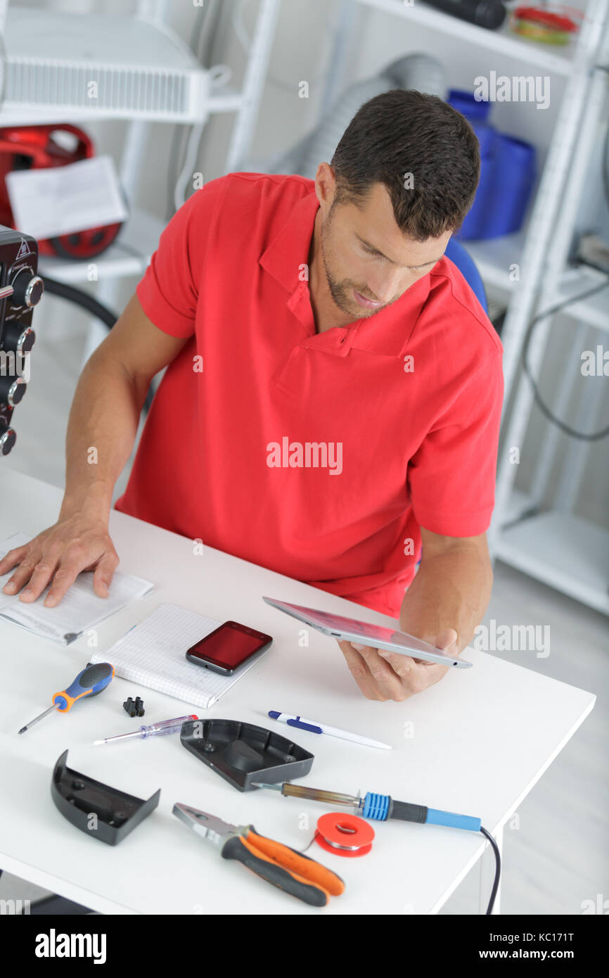 man checking on tablet how to fix something Stock Photo - Alamy