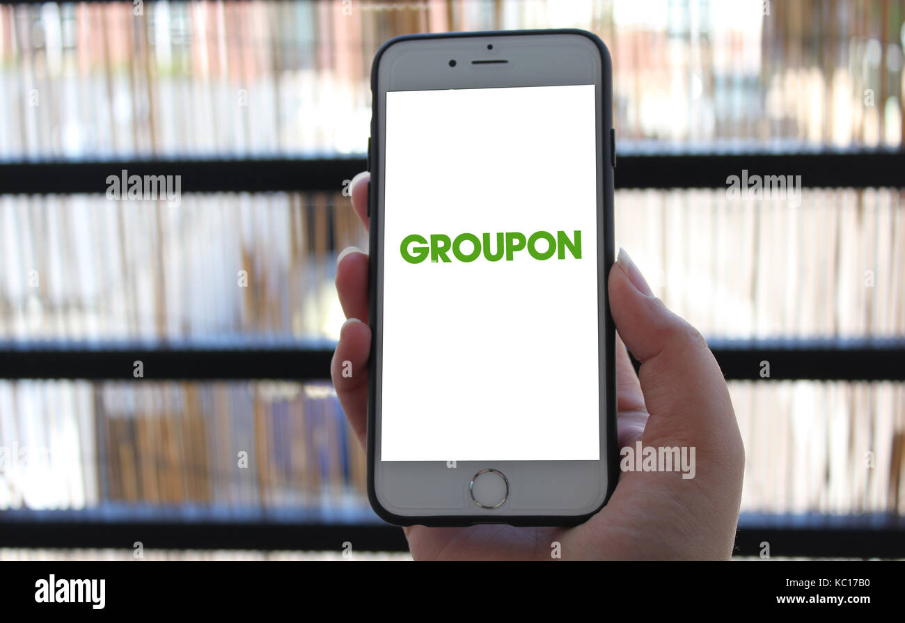 Consumer holding phone with Groupon logo Stock Photo - Alamy