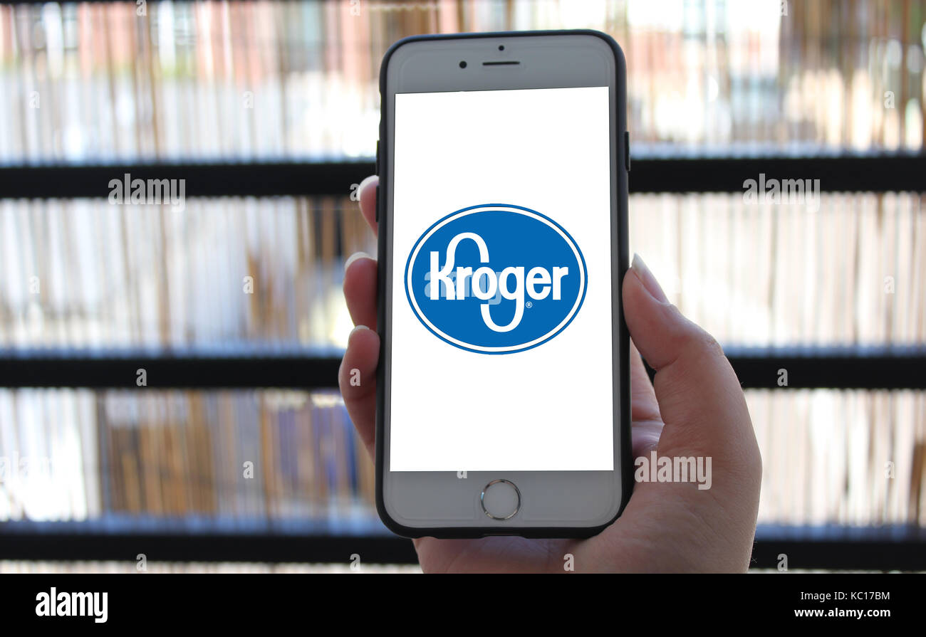 Consumer holding phone with Kroger logo Stock Photo - Alamy
