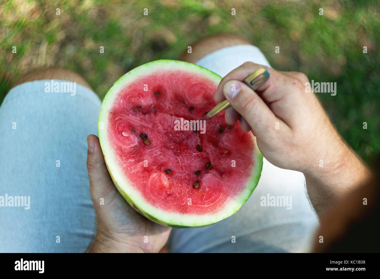 A young man is eating a watermelon with a spoon. The concept of healthy ...