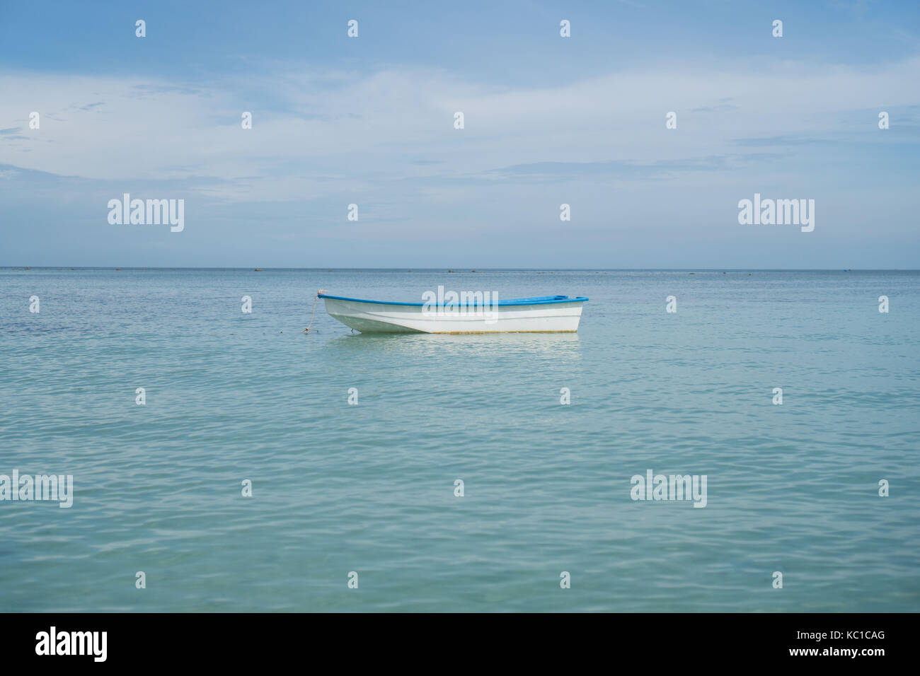 Small single fishing boat floating on the calm sea over blue sky ...