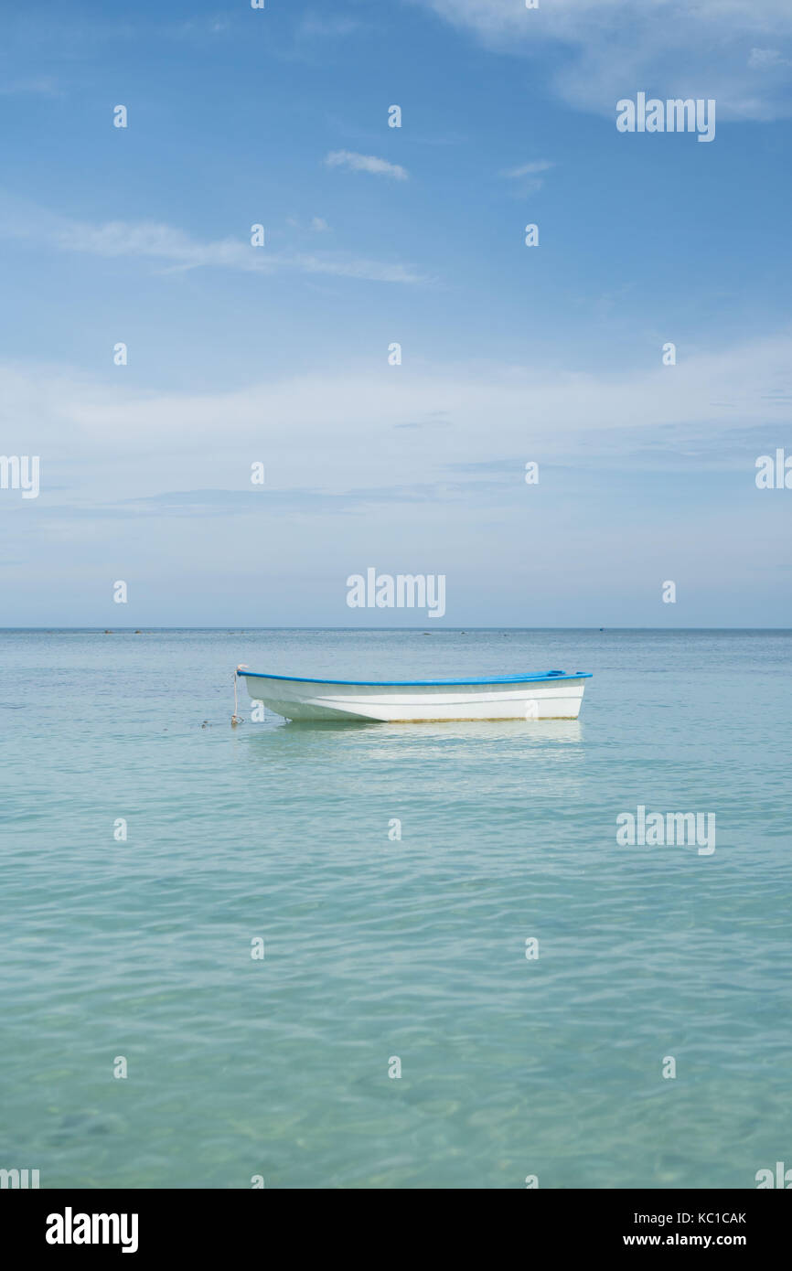 Small single fishing boat floating on the calm sea over blue sky ...