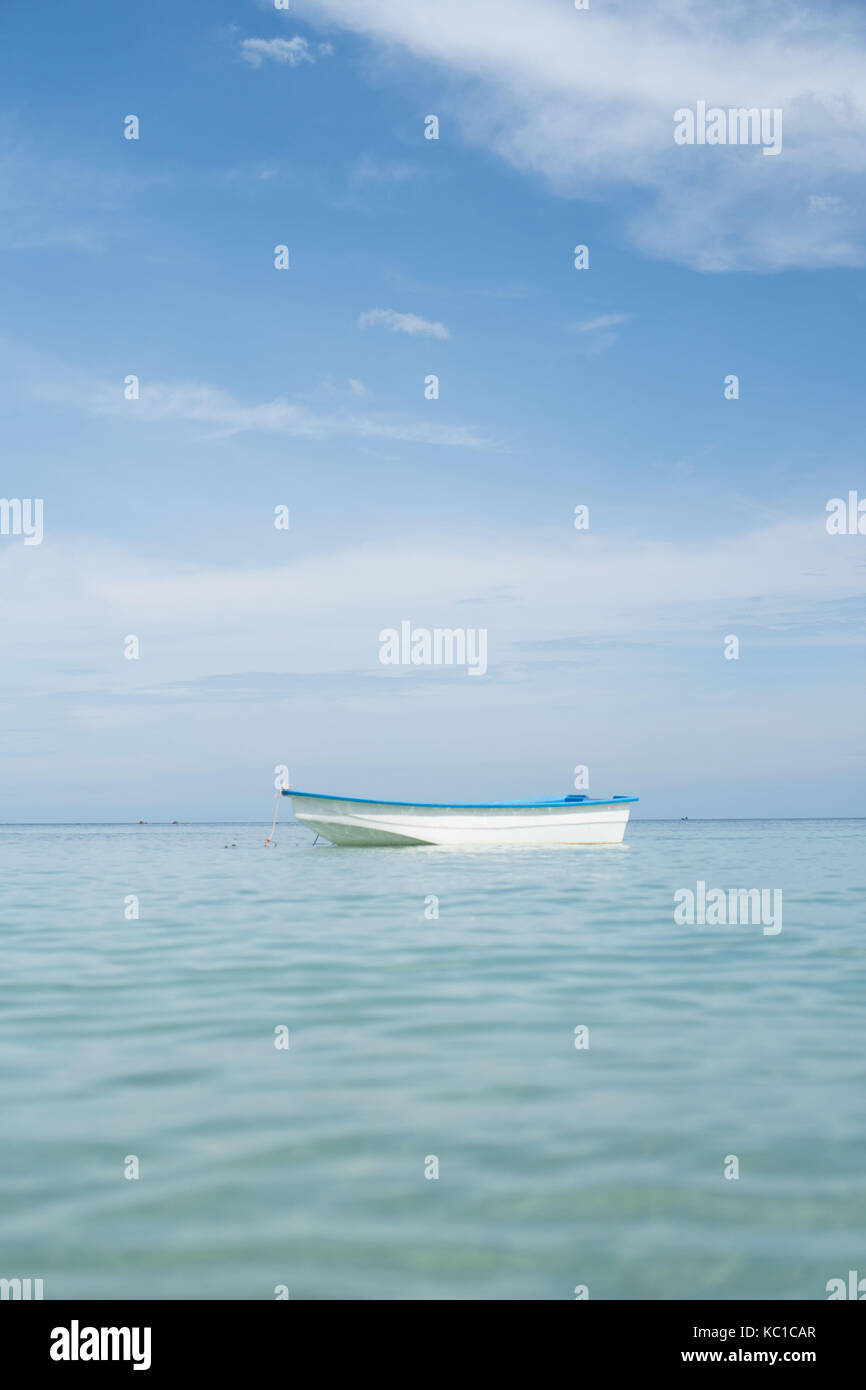 Small single fishing boat floating on the calm sea over blue sky ...