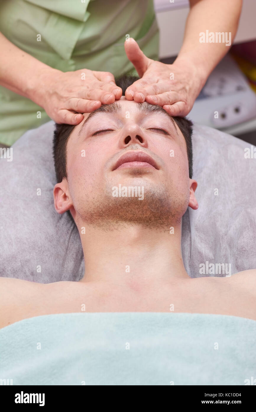 Handsome man getting face massaged Stock Photo - Alamy