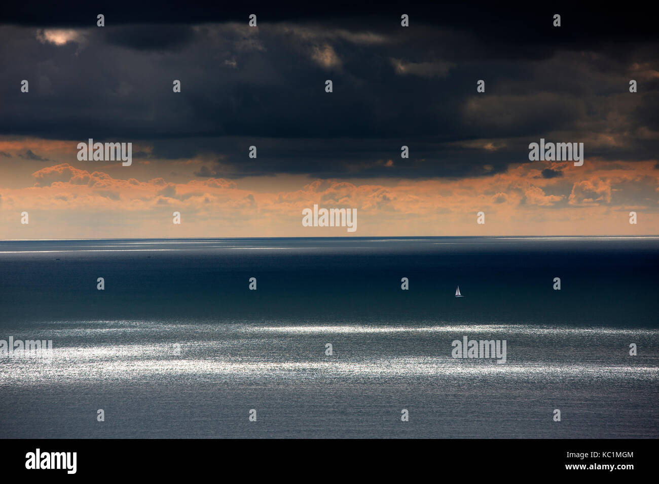 Distant view of sailing boat, yacht, on the sea with storm clouds and ...
