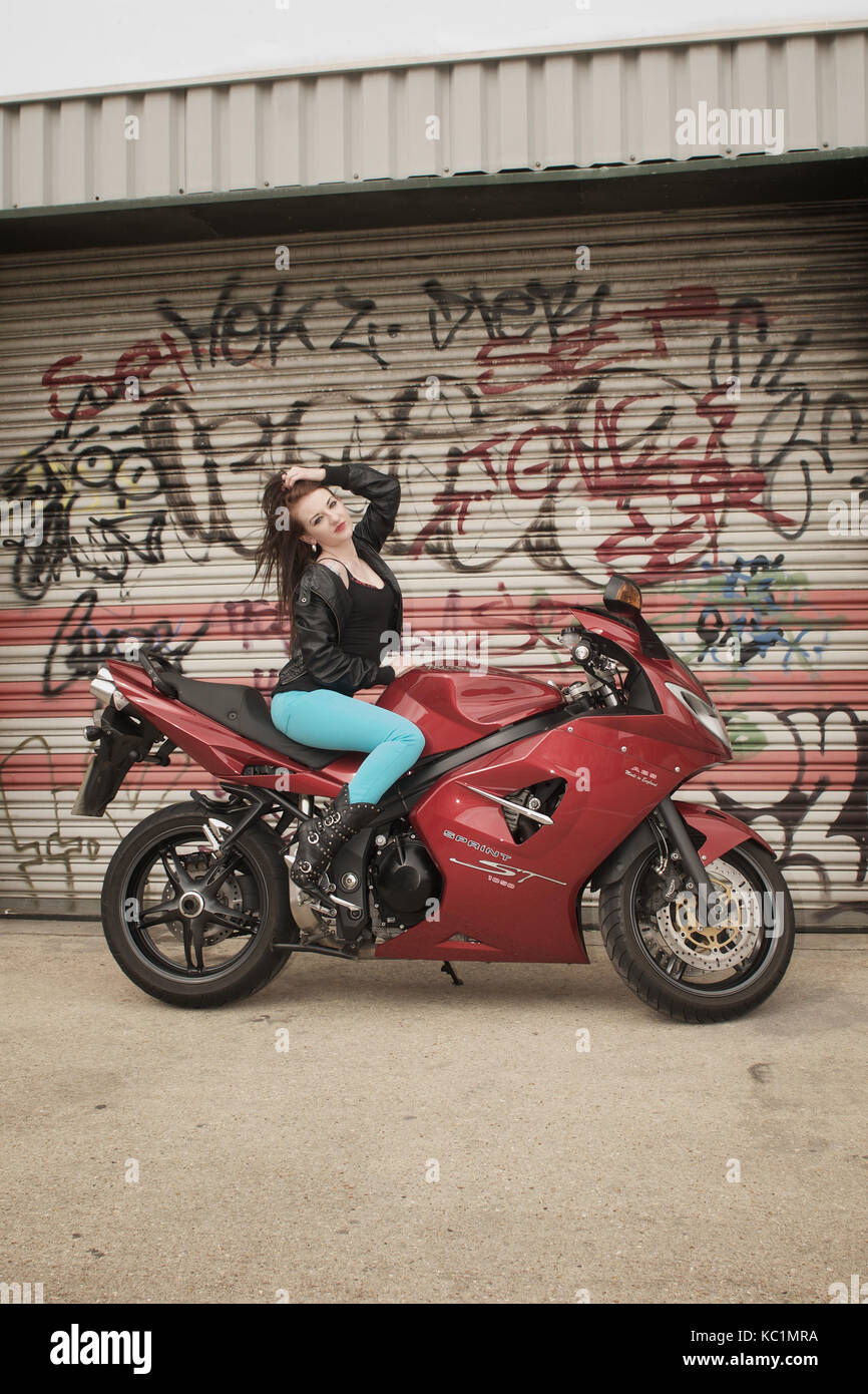 Pretty brunette girl on a Triumph Sprint 1050 motorcycle in an urban ...