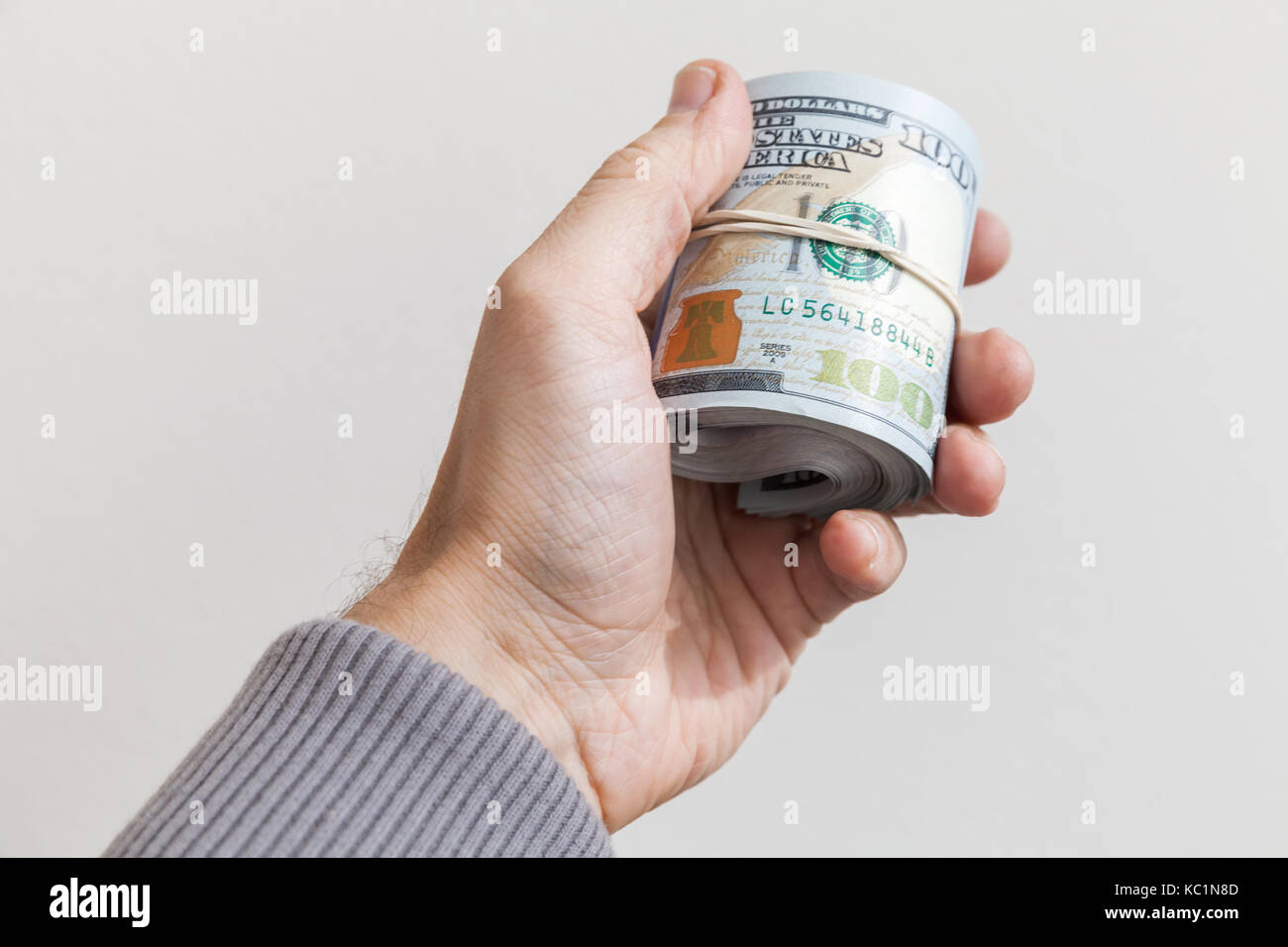 Roll of new One Hundred Dollars notes in male hand Stock Photo - Alamy