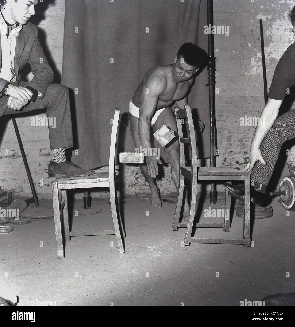 1960s, historical, young black male athlete in a gym with two men ...