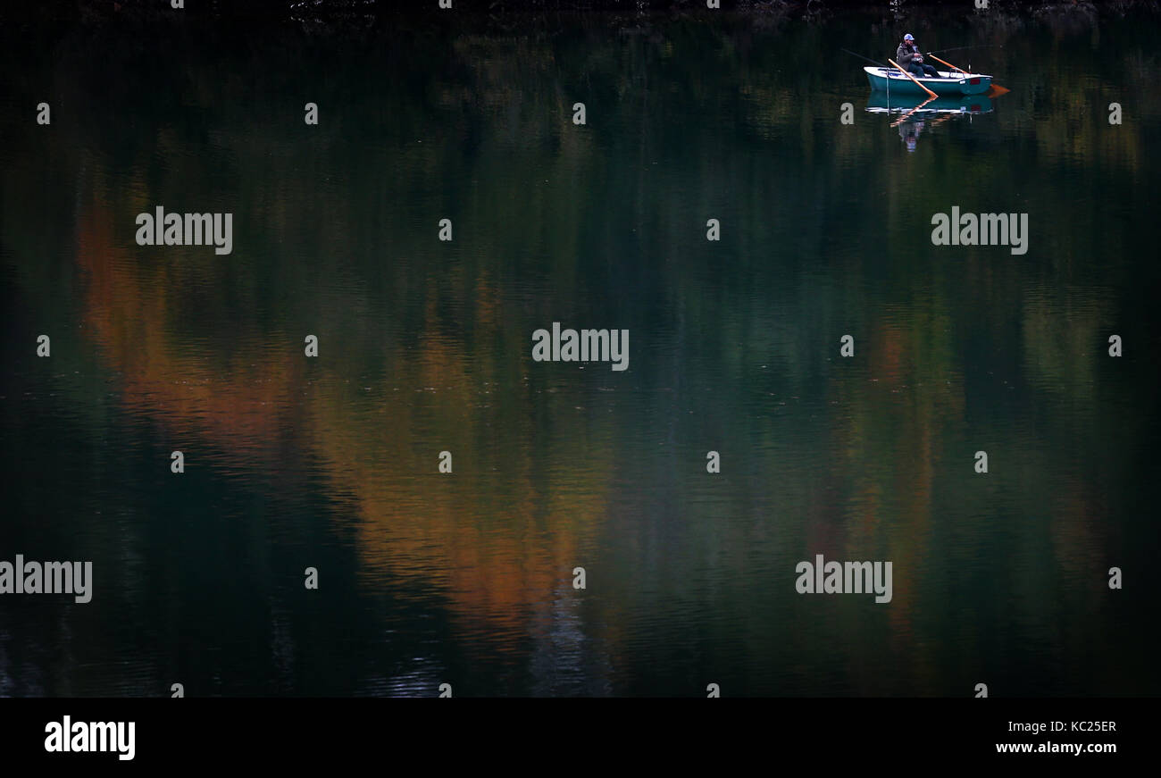 A person can be seen fishing on lake Forggensee, in which the ...